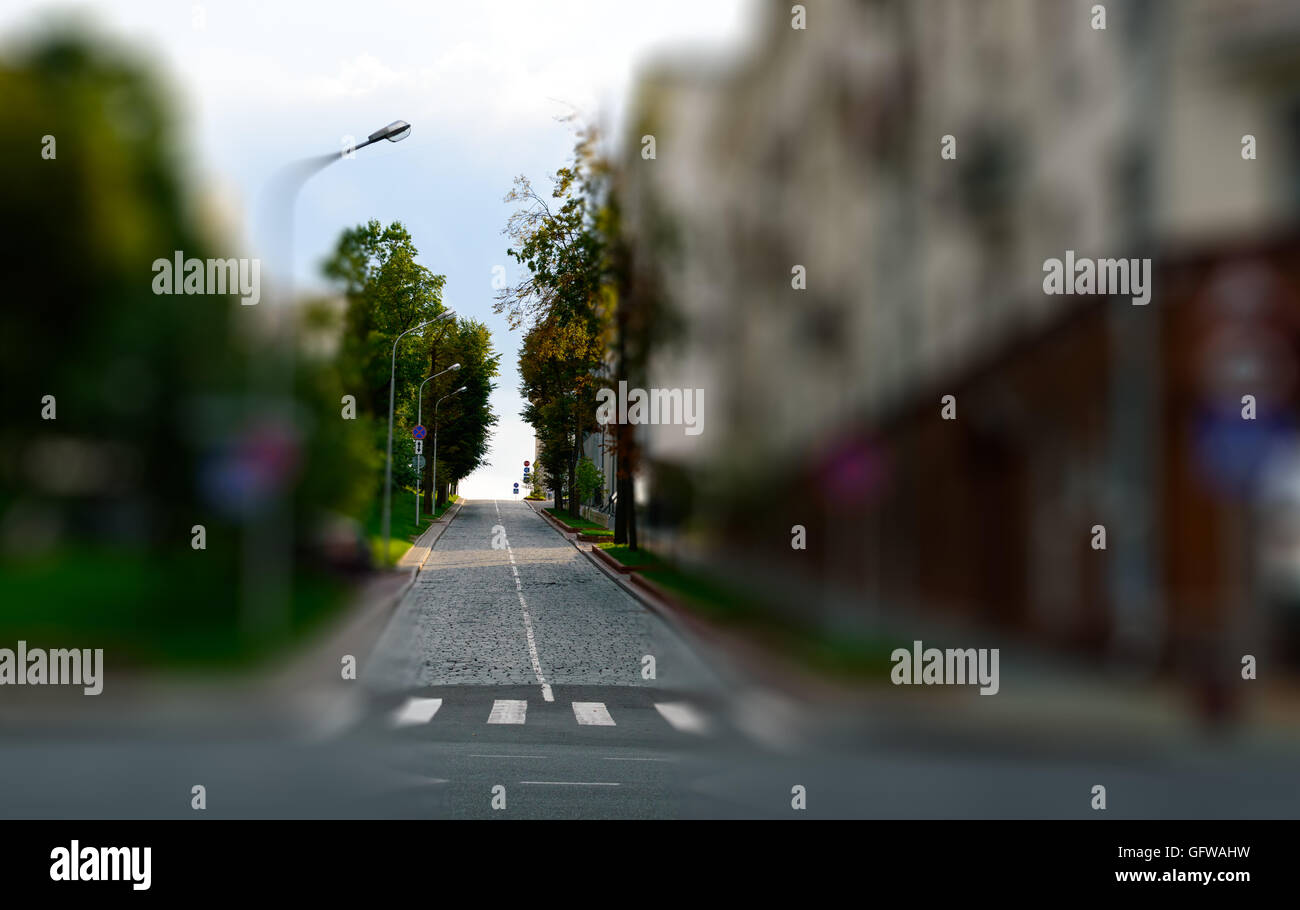 Tilt-shift city street with cross walk. Traffic signs and buildings ...