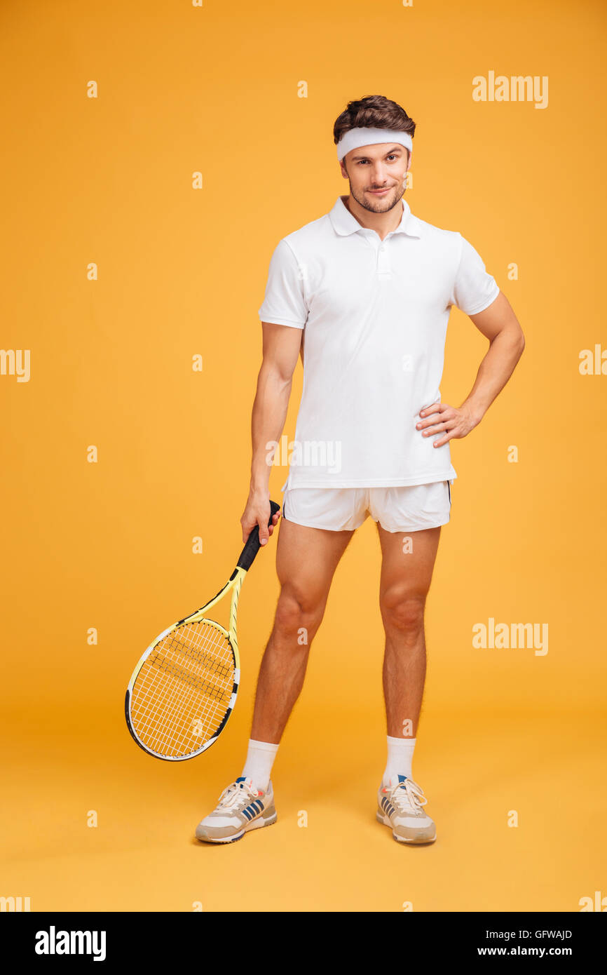 Full length of attractive young man tennis player standing and holding ...
