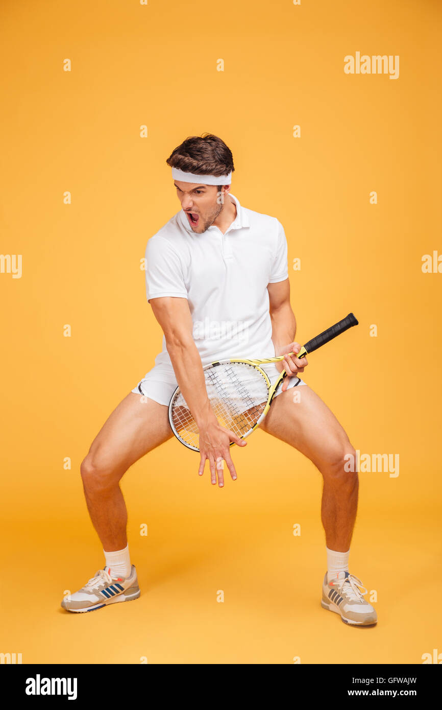 Funny playful young man tennis player with racket imitating playing ...