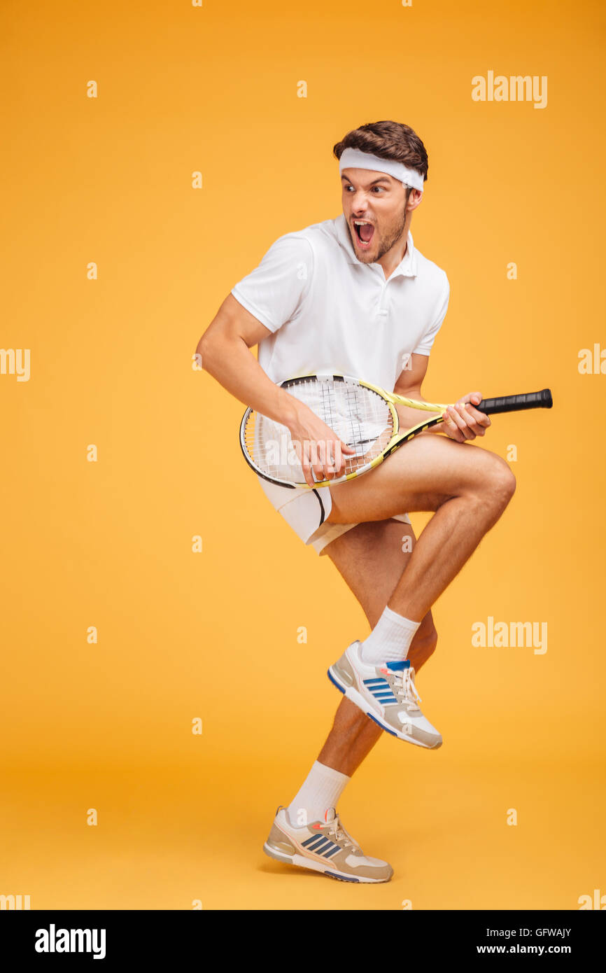Comical young man tennis player with racket shouting and joking over ...