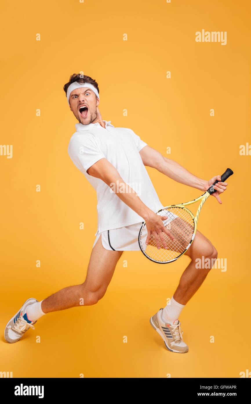 Funny cute young man tennis player with racket singing and imitating ...