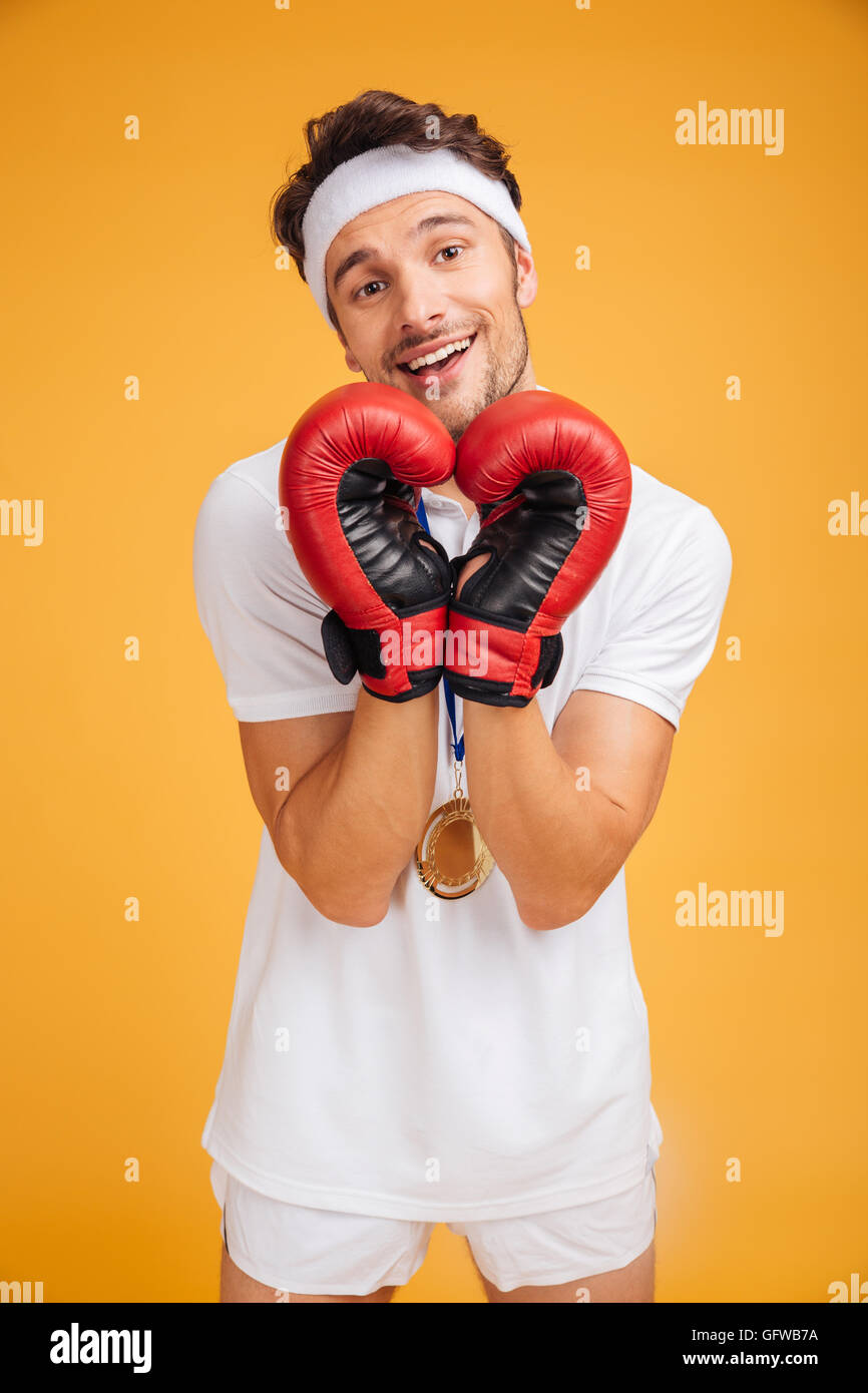 Happy cute young man boxer in red gloves making heart by hands over ...