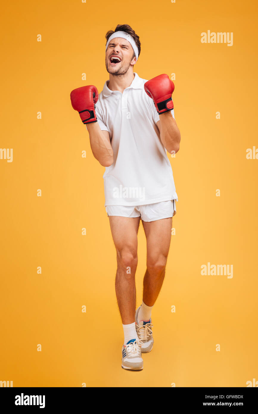 Full length of happy young man boxer in red gloves celebrating success ...