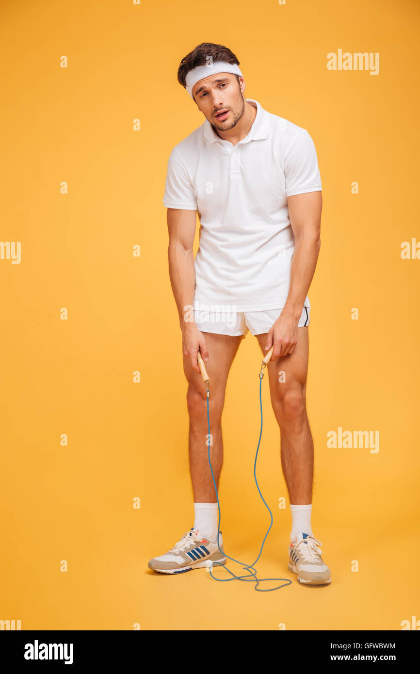 Full length portrait of a young handsome tired sportsman holding ...