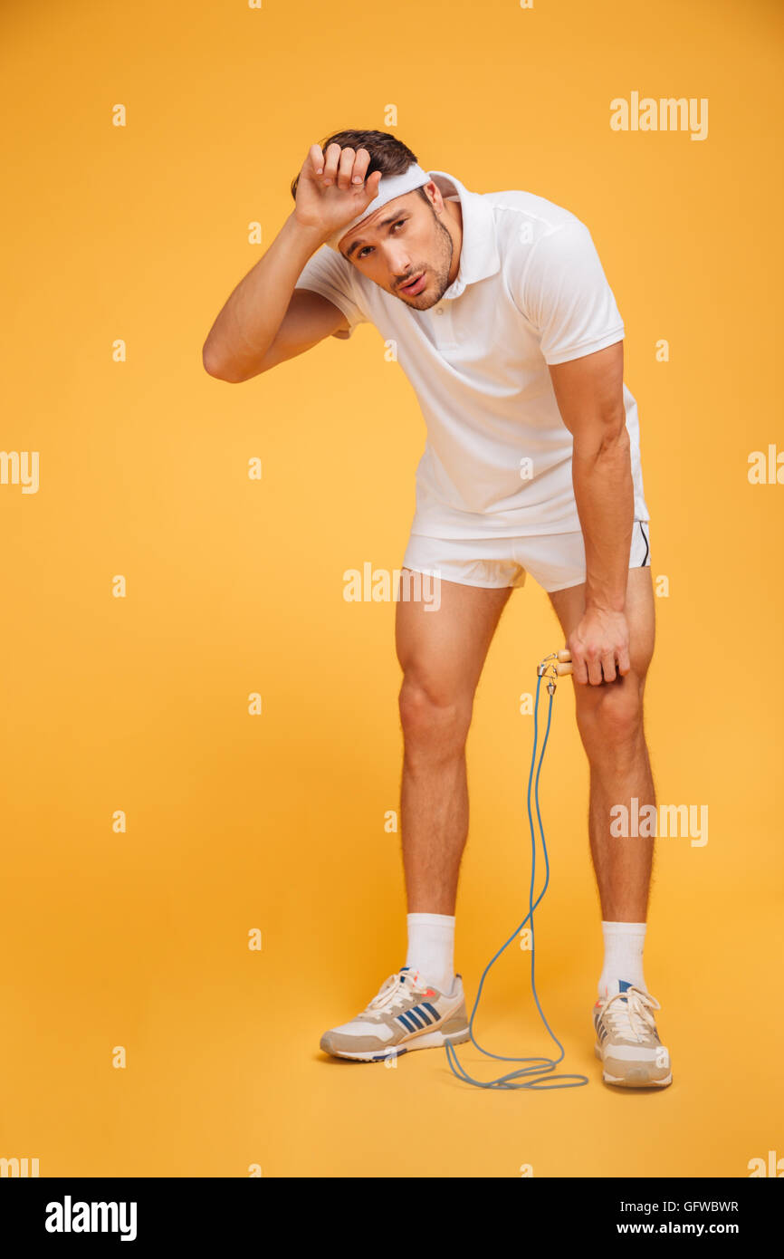 Full length portrait of a young handsome tired sportsman holding ...