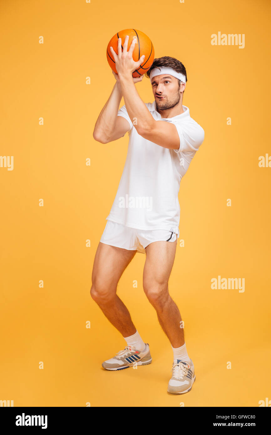 Portrait of a handsome young concentrated man playing basketball ...