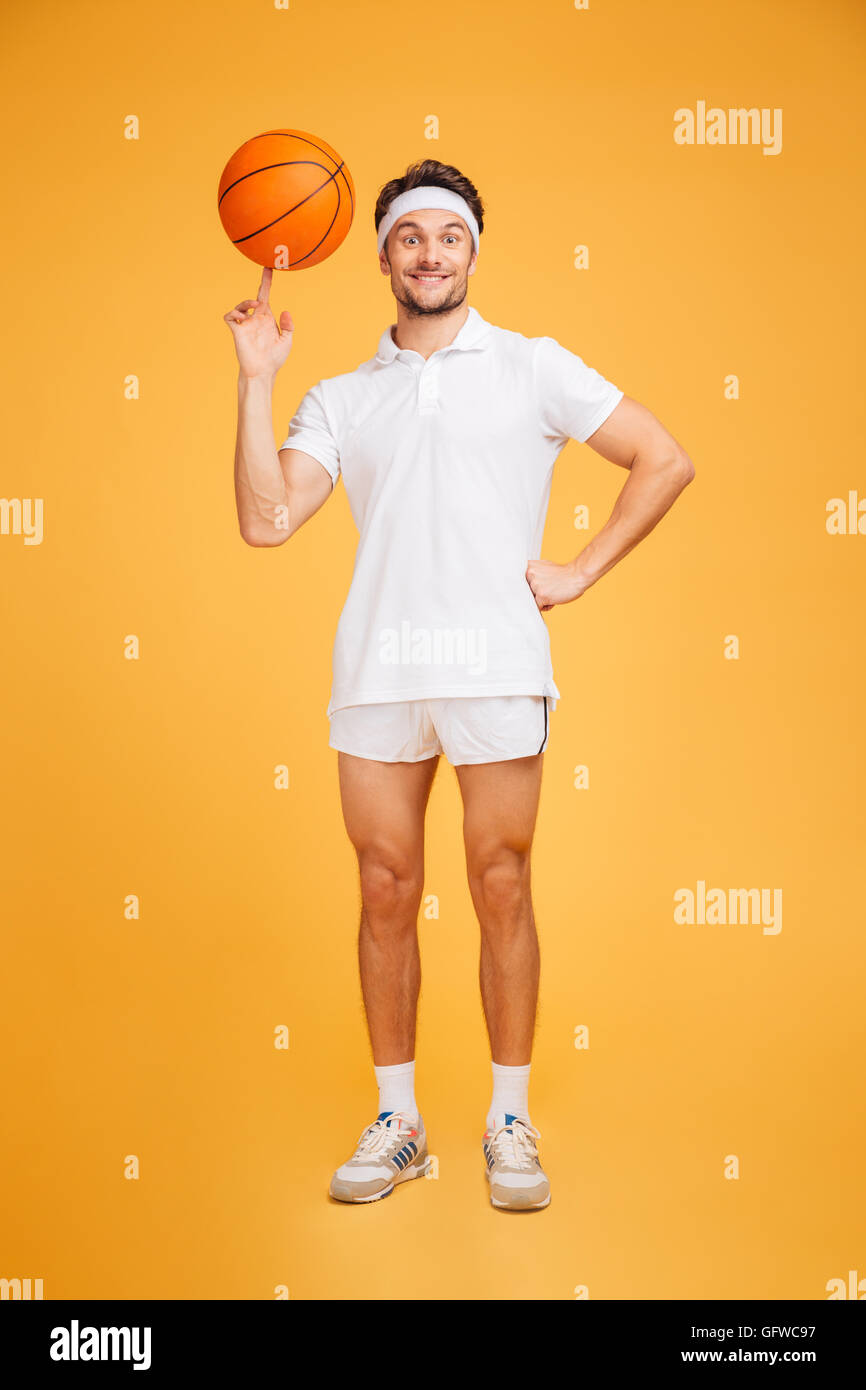 Smiling basketball player spinning ball on his finger isolated on a ...