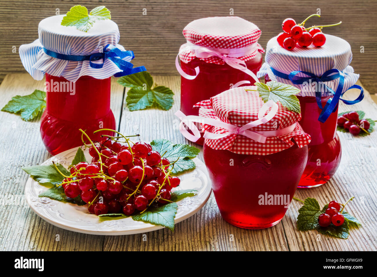 Preserved homemade red currant jam in glass jars on white wooden table ...