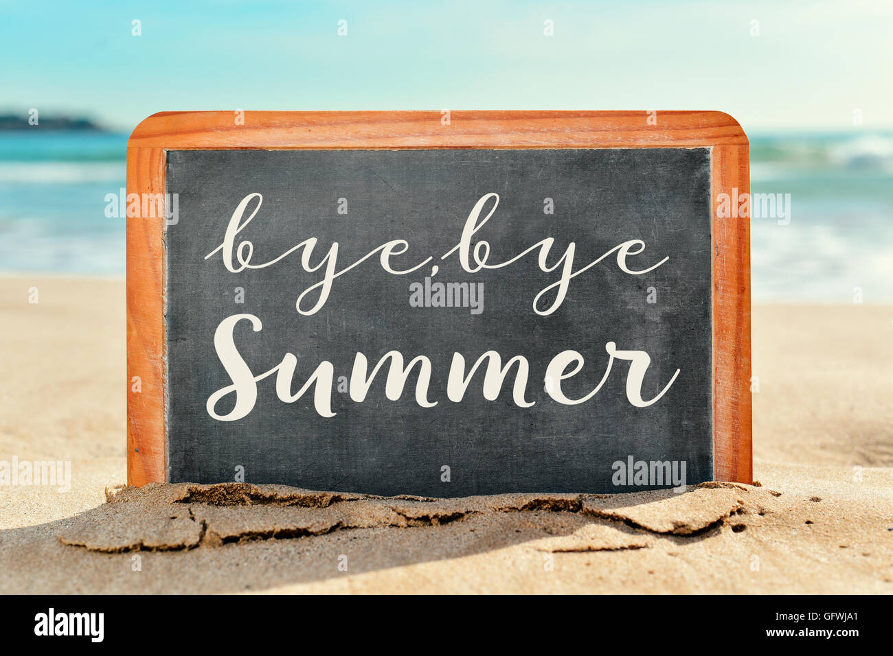 closeup of a chalkboard with the text bye, bye summer written in it, on the sand of a beach ...