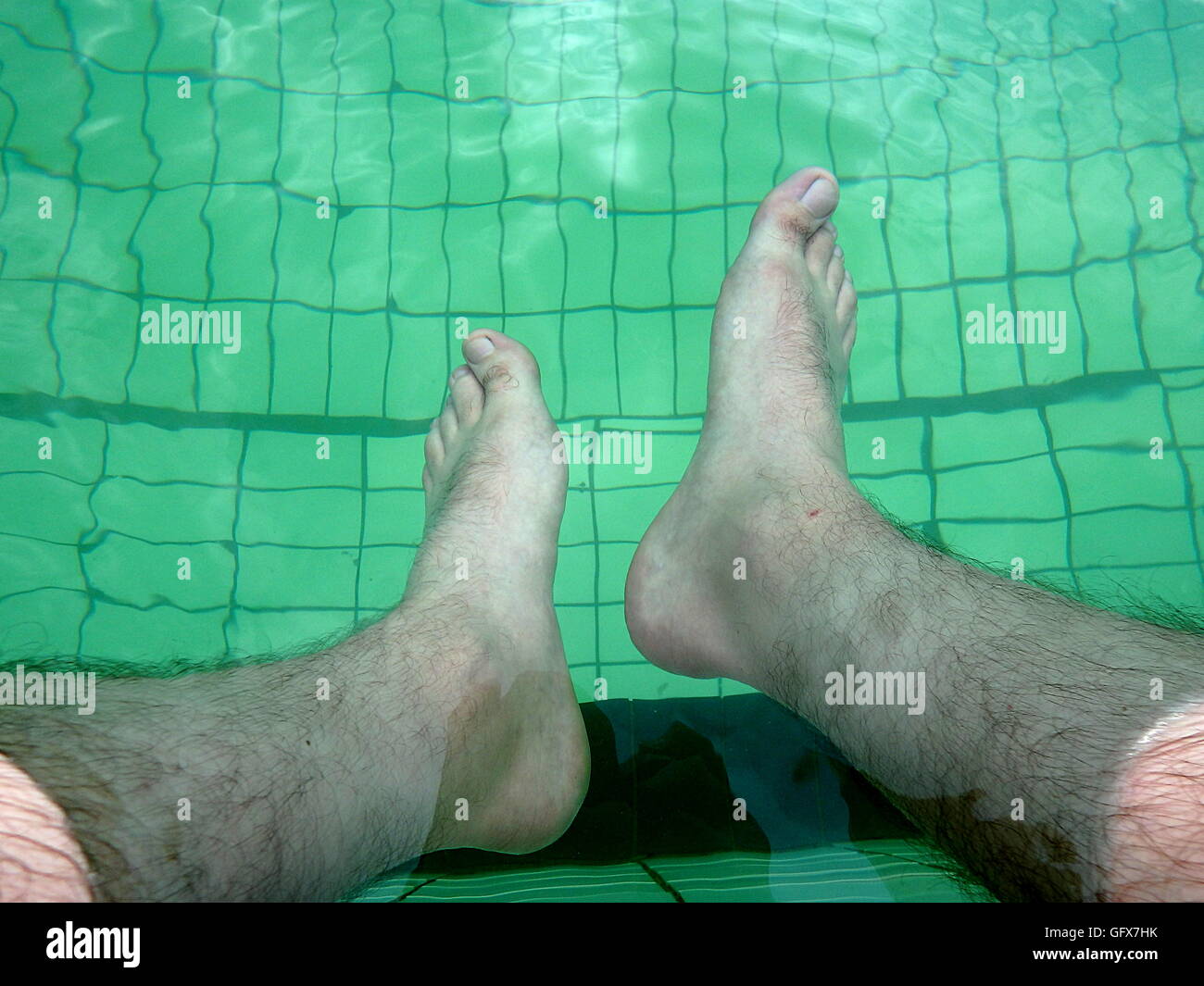 legs in the pool, feet in the clear water Stock Photo - Alamy