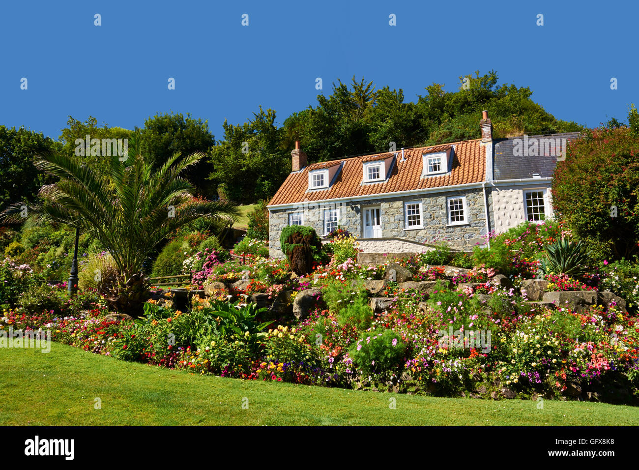 Cottage flower beds and lawn against blue sky Stock Photo - Alamy