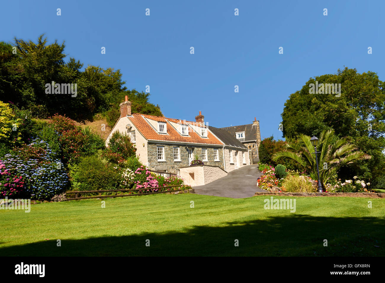 Cottage flower beds and lawn against blue sky Stock Photo - Alamy
