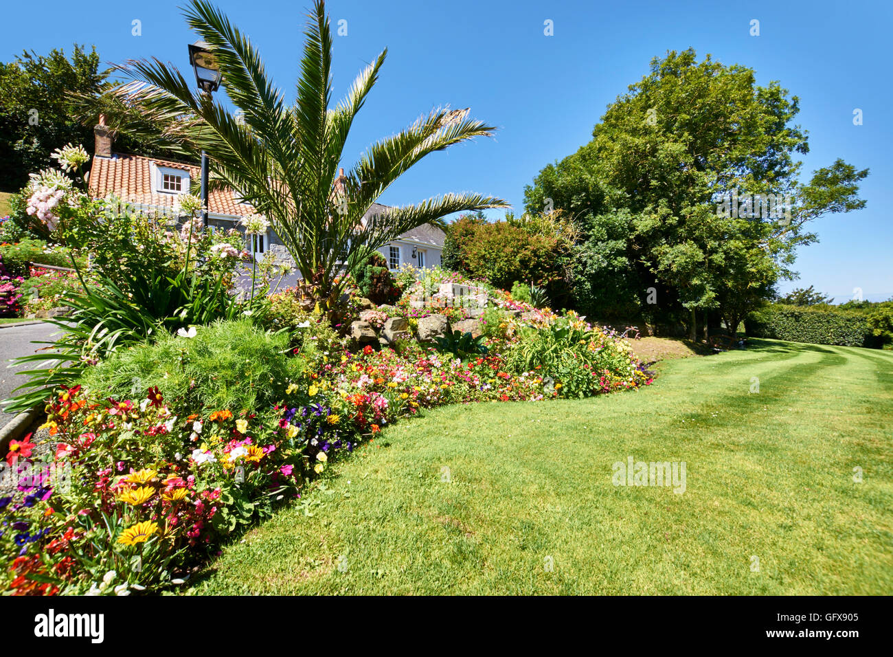 Cottage flower beds and lawn against blue sky Stock Photo - Alamy
