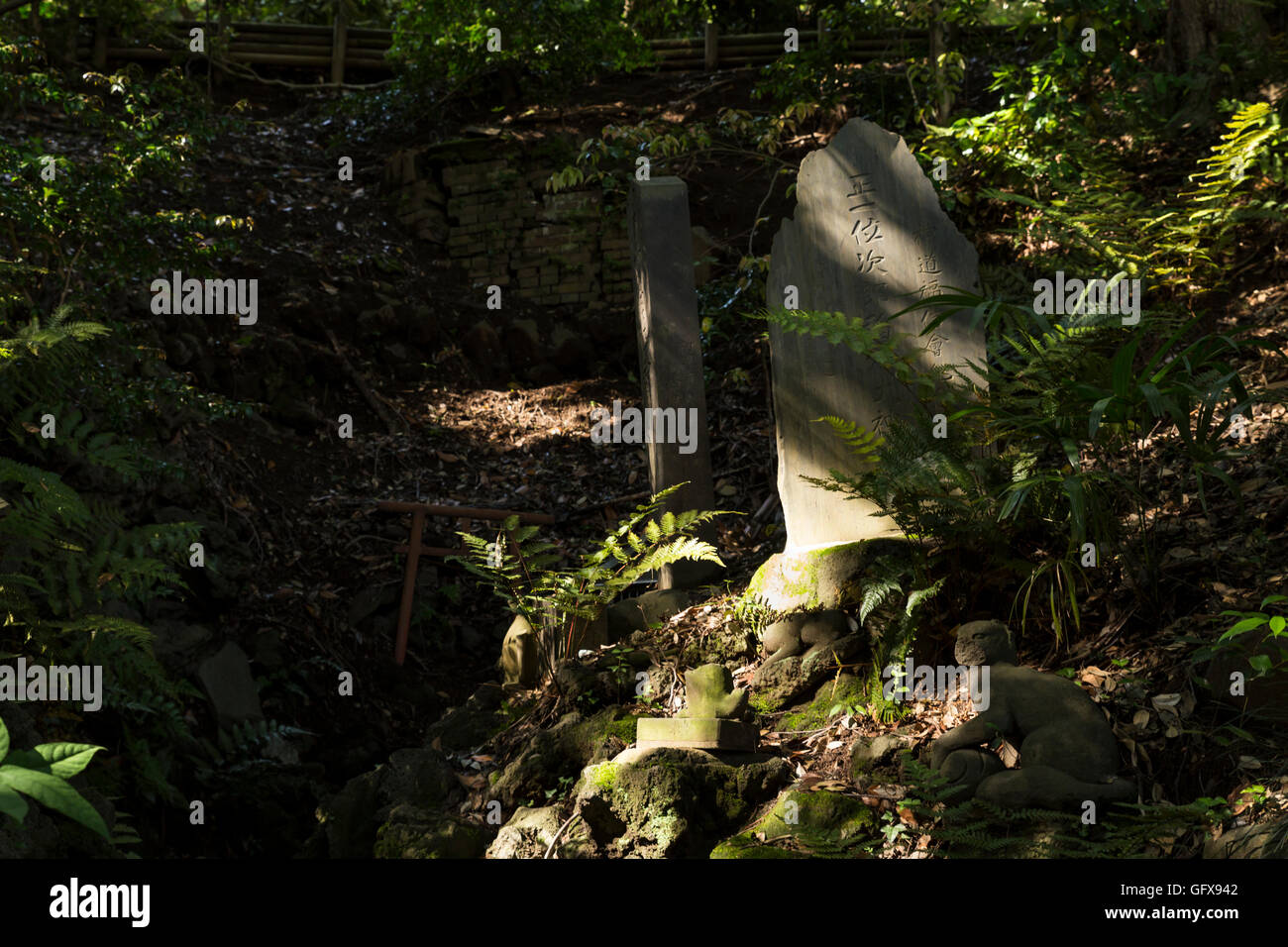 A small hidden shrine with a stone memorial tablet in a Japanese forest ...