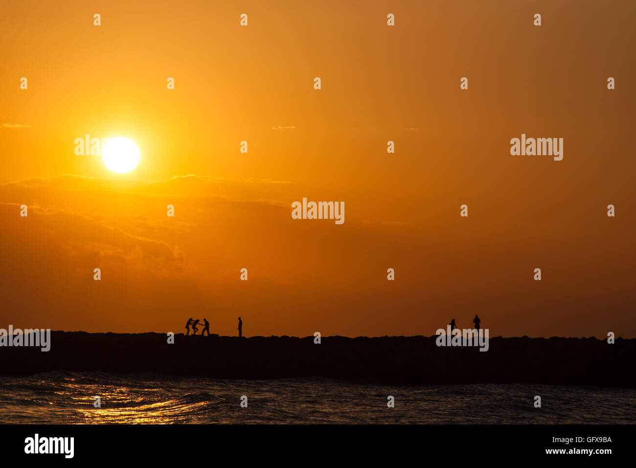 People enjoying the beautiful sunset next to the sea Stock Photo - Alamy