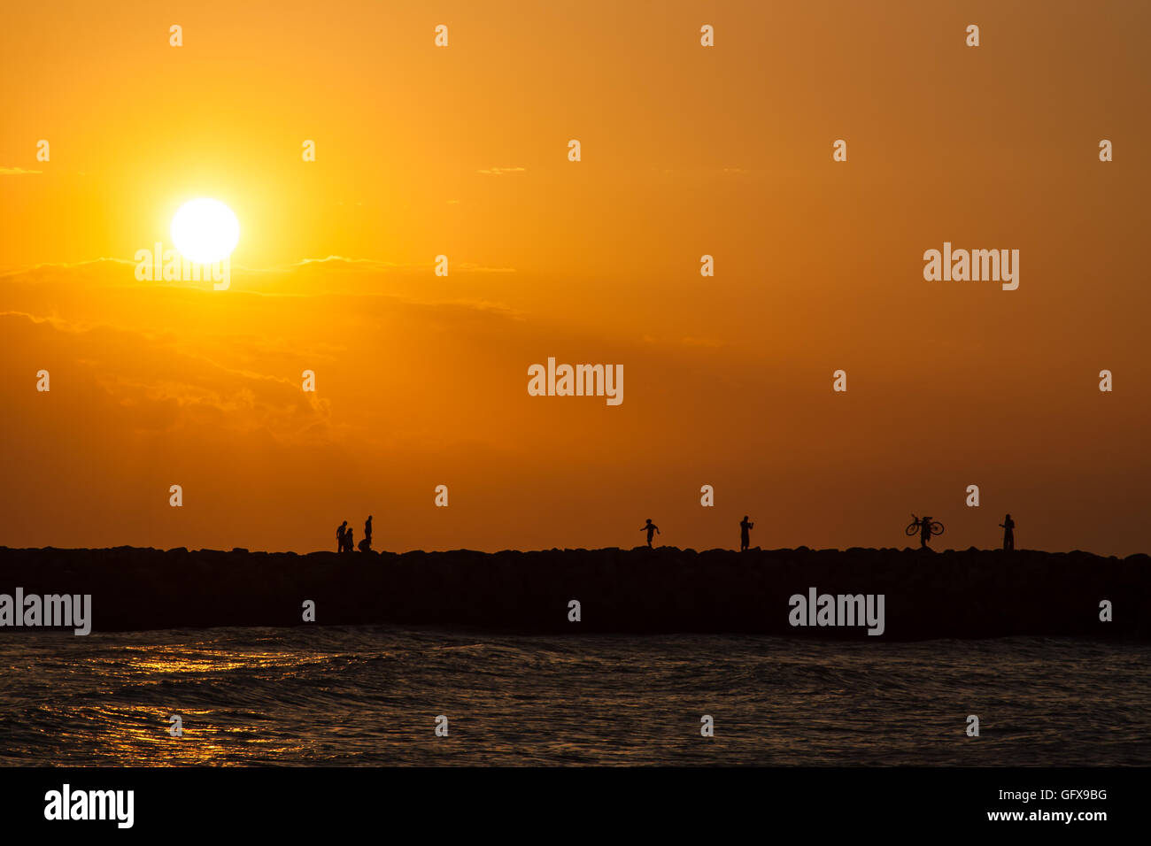 People enjoying the beautiful sunset next to the sea Stock Photo - Alamy