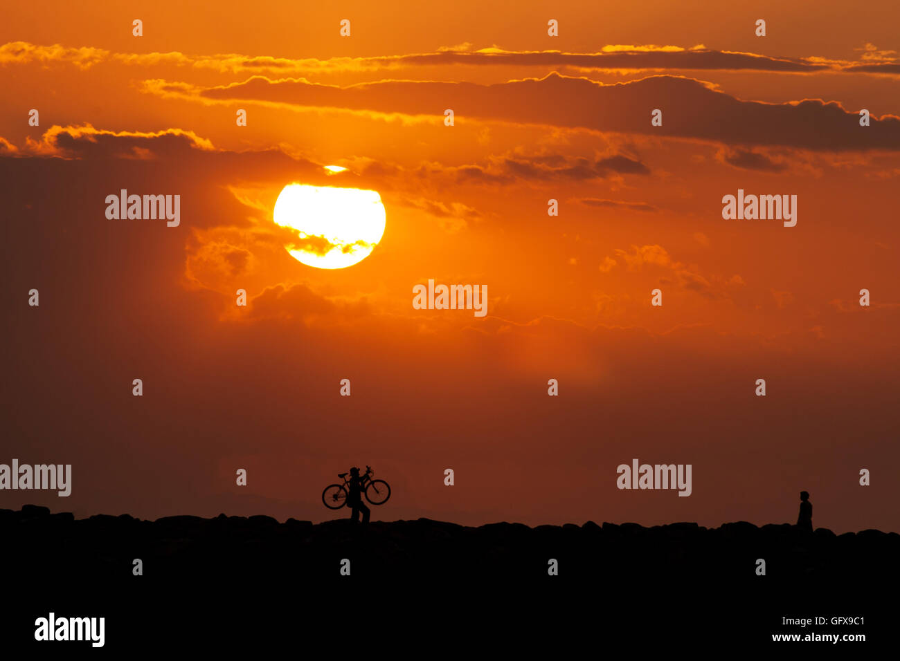 Man carrying his bicycle at sunset Stock Photo - Alamy