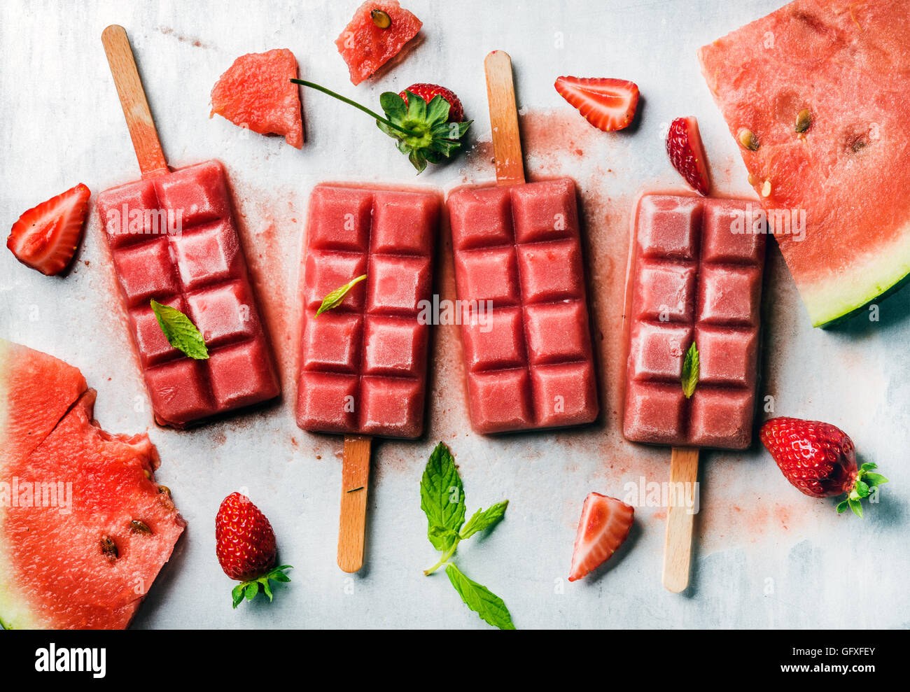 Strawberry watermelon ice cream popsicles with mint over steel tray ...