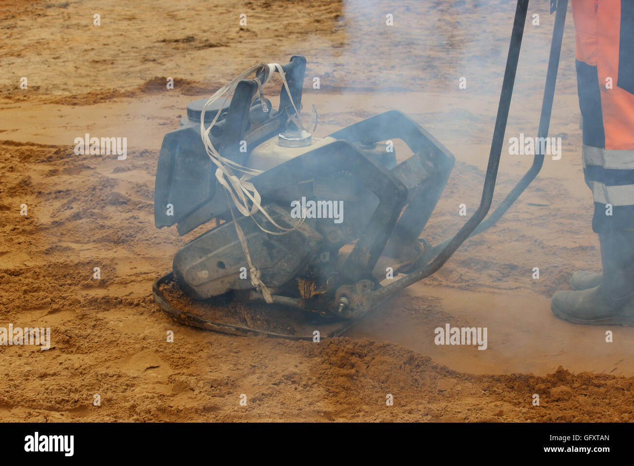 mason tamps the soil using plate compactor before laying paving slabs ...