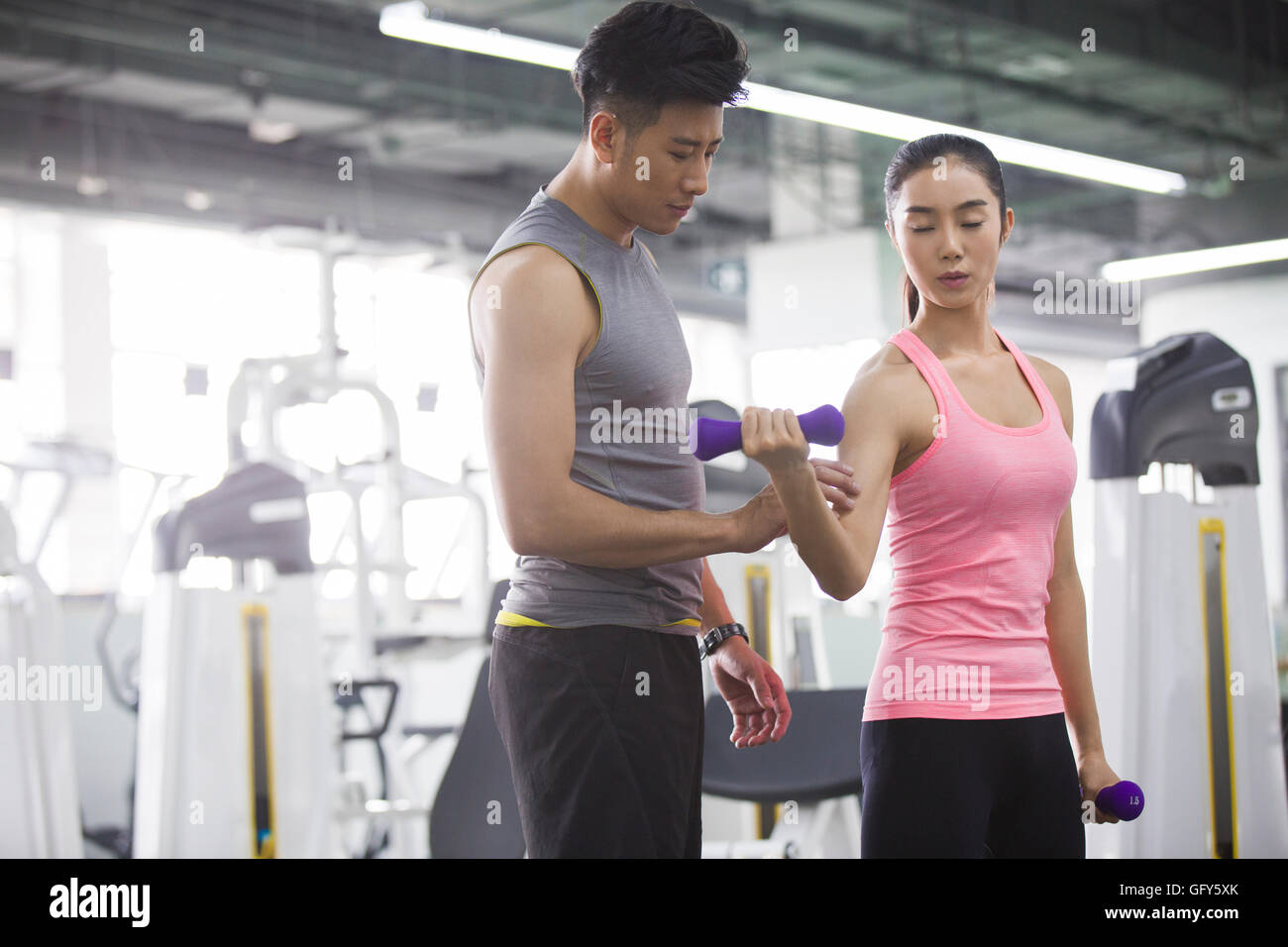 Young Chinese woman working with trainer at gym Stock Photo - Alamy