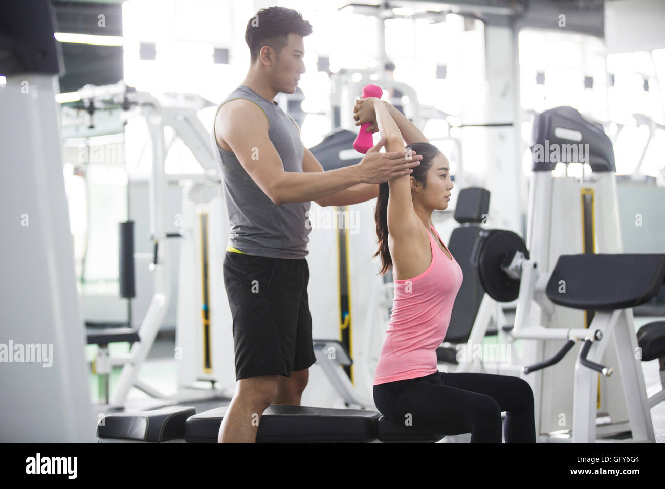 Young Chinese woman working with trainer at gym Stock Photo - Alamy