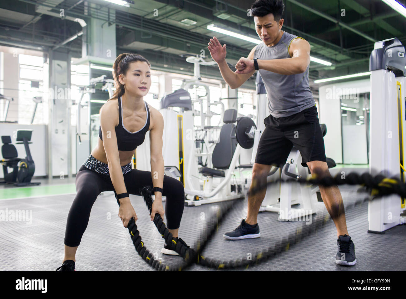 Young Chinese woman working with trainer at gym Stock Photo - Alamy