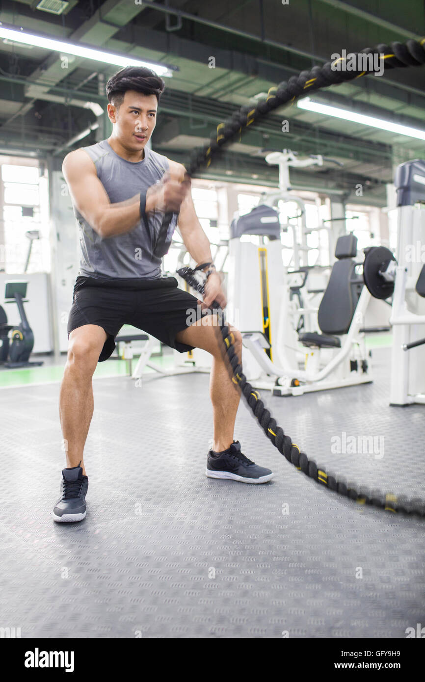 Young Chinese man exercising with battling rope at gym Stock Photo - Alamy