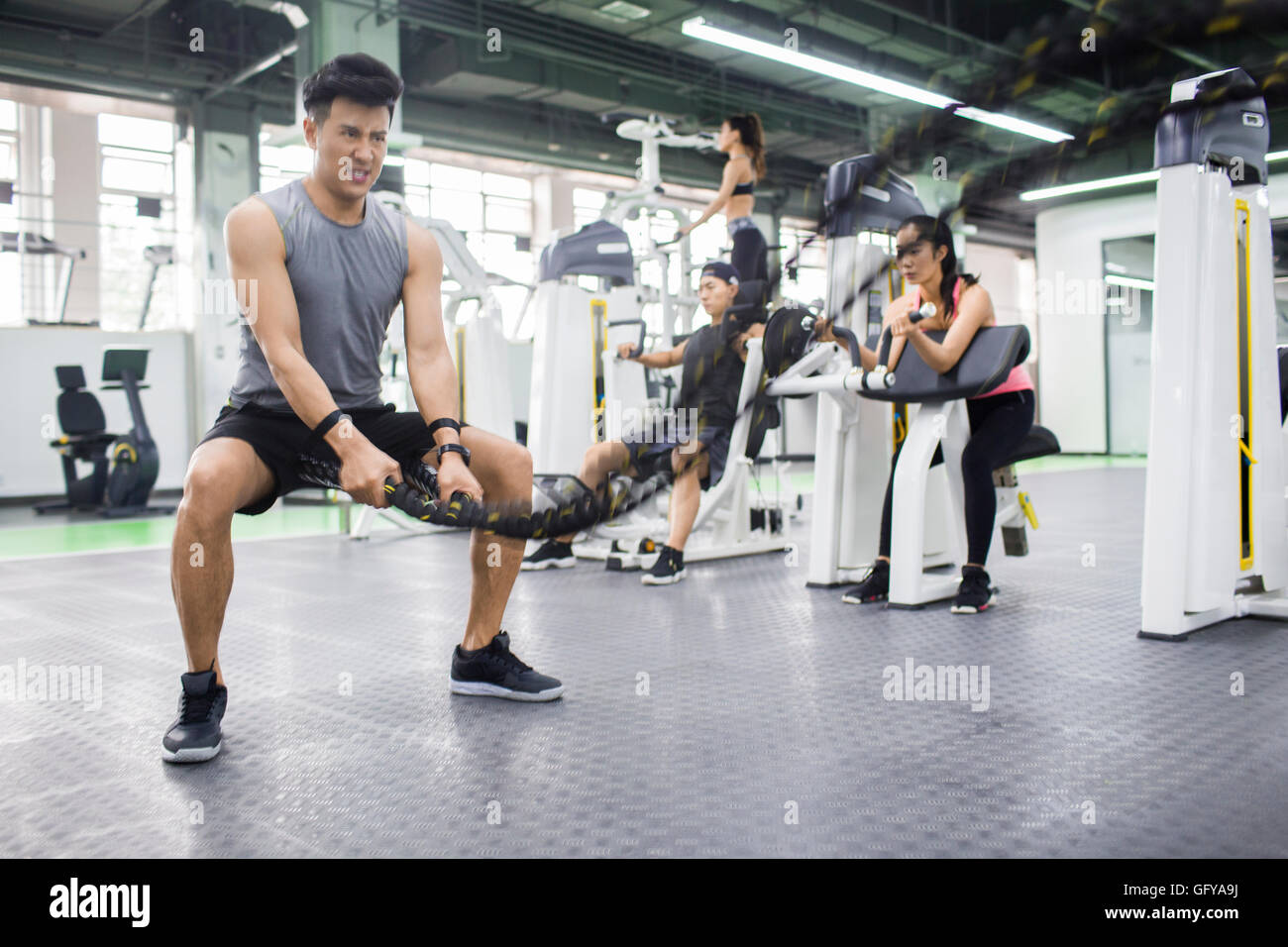 Young Chinese man exercising with battling rope at gym Stock Photo - Alamy