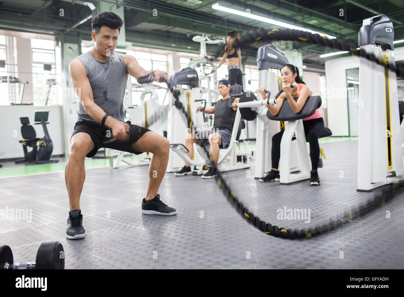 Young Chinese man exercising with battling rope at gym Stock Photo - Alamy
