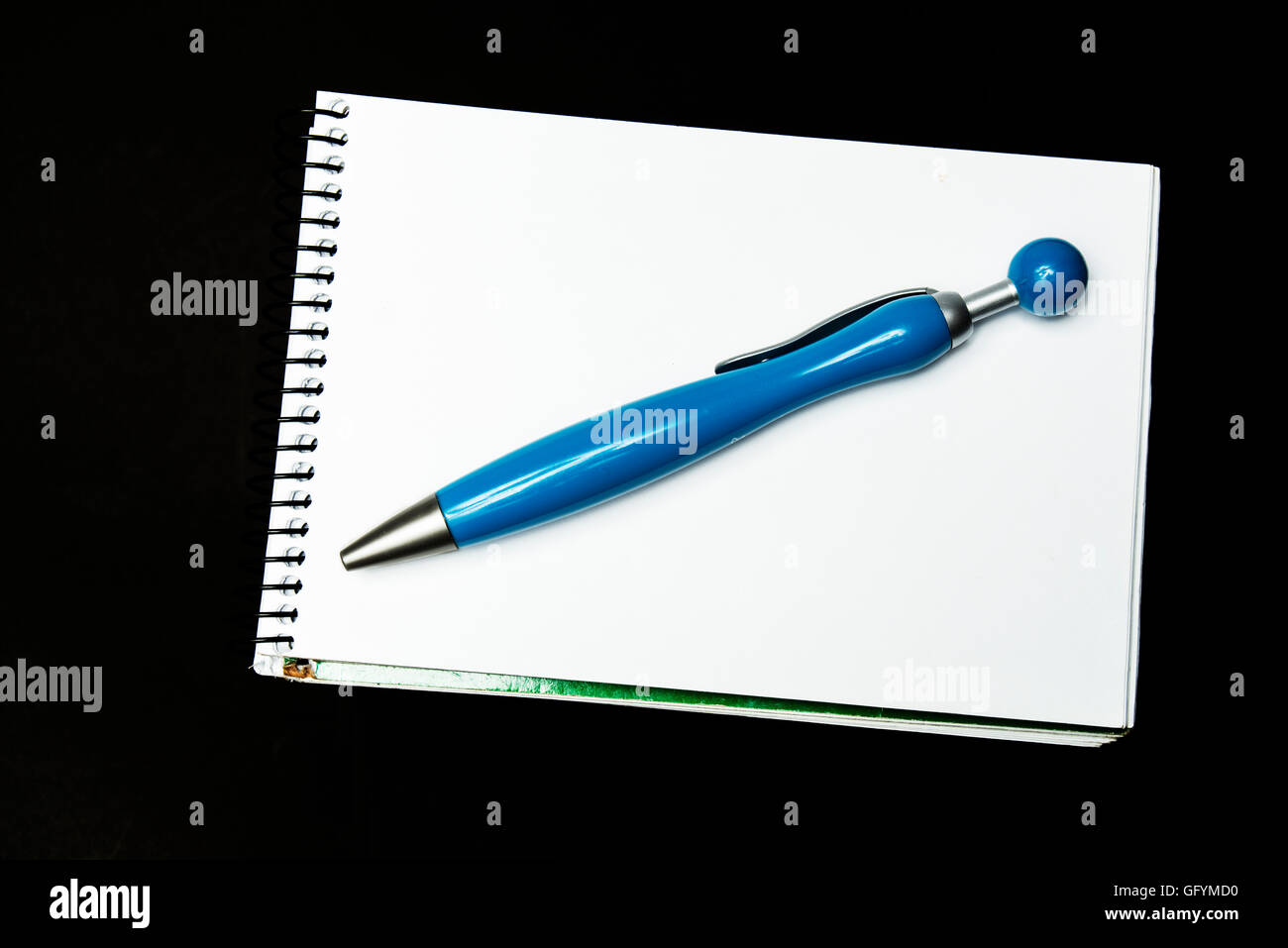 blue pen on notebook on black background Stock Photo - Alamy