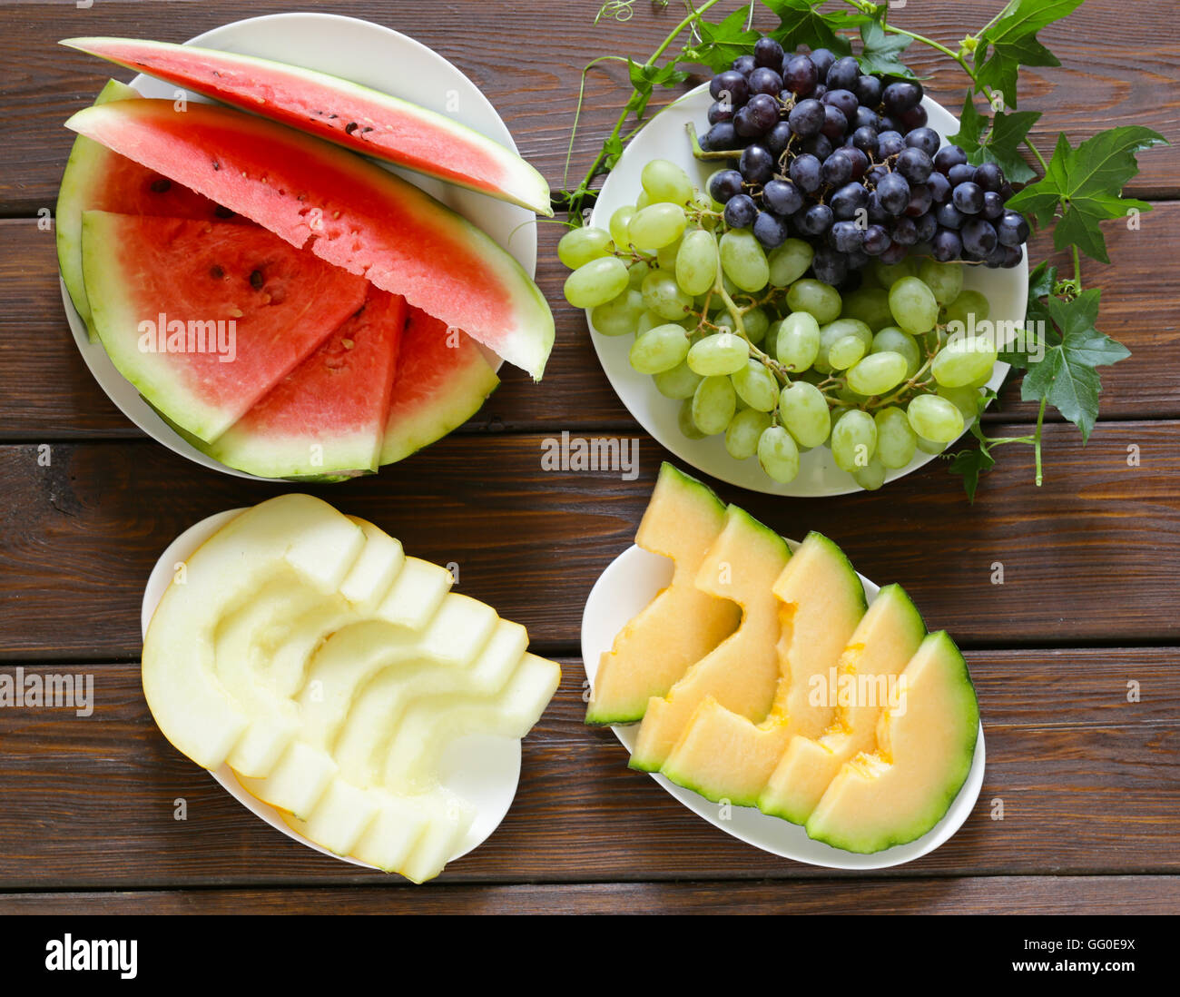 ripe organic fruit watermelon, melon cantaloupe and grapes on a wooden ...