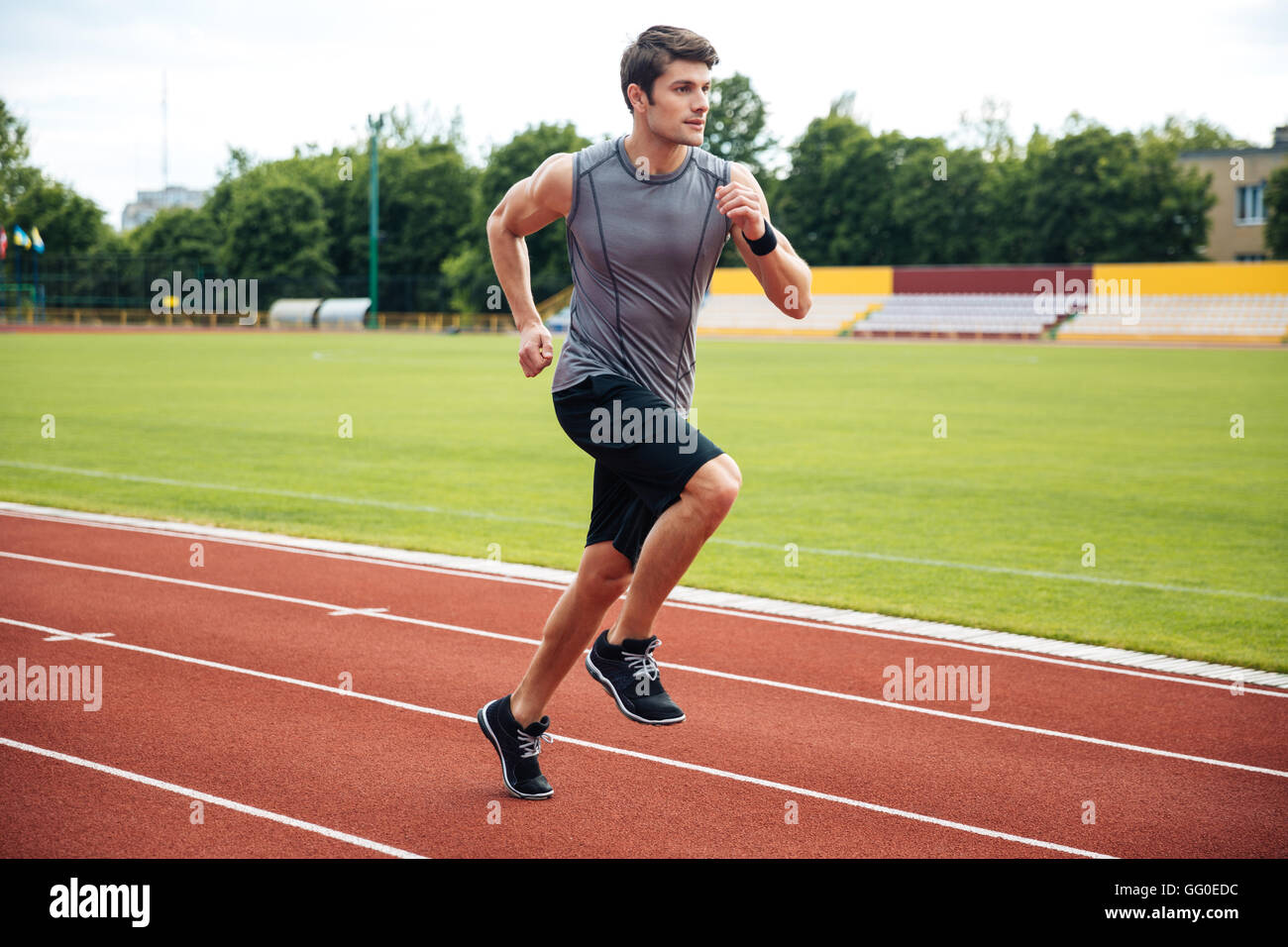 Portrait of a young male athlete training on a race track at the ...