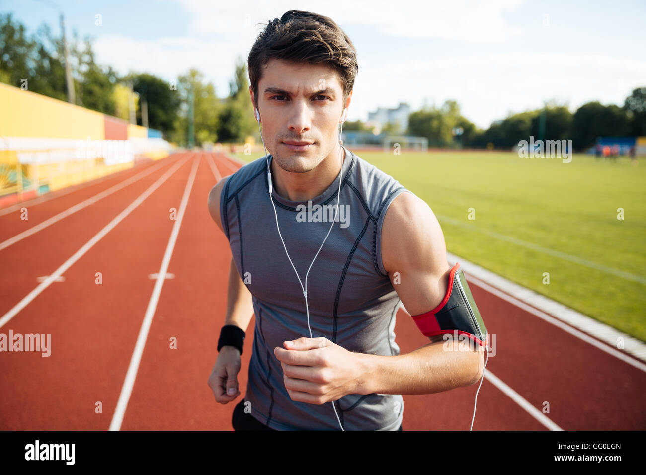 Close up portrait of a young handsome sports man running down stadium ...