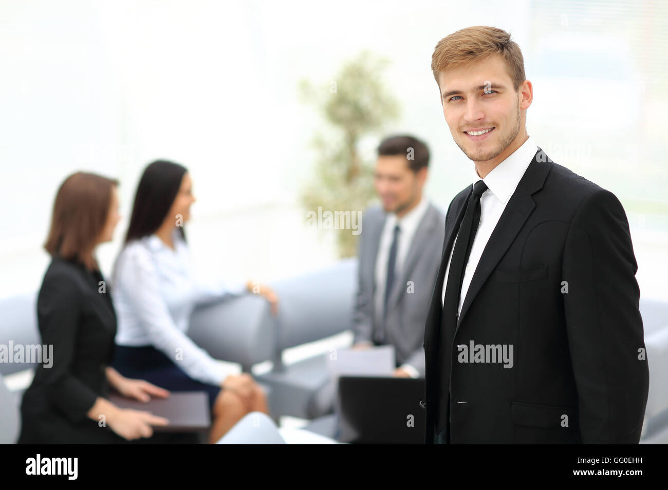 Successful business man standing with his staff in background at Stock ...