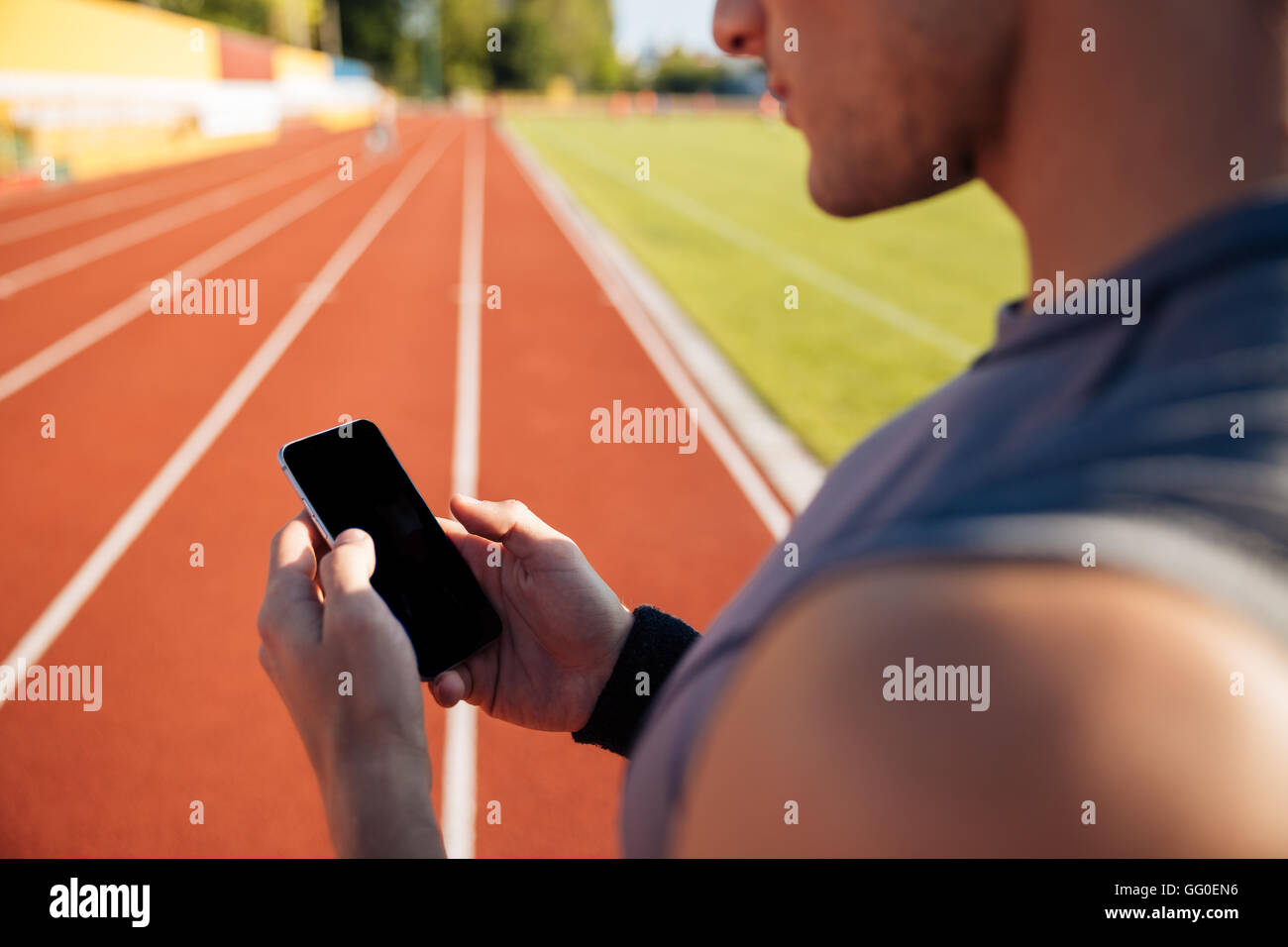 Cropped image of a handsome man resting after run and using smartphone ...