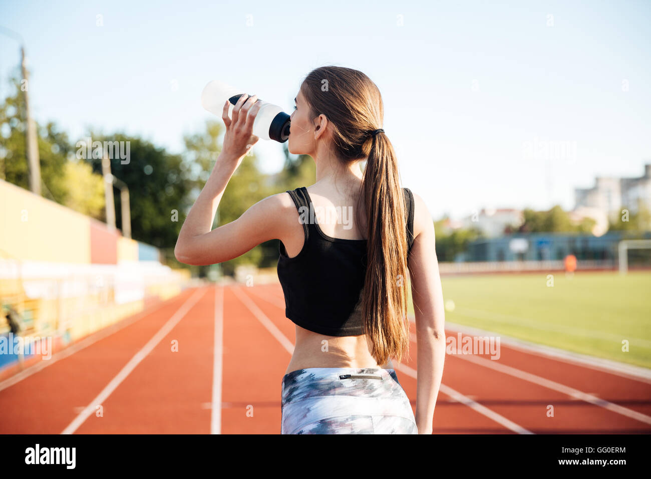 Young female athlete drinking from water bottle after workout at ...