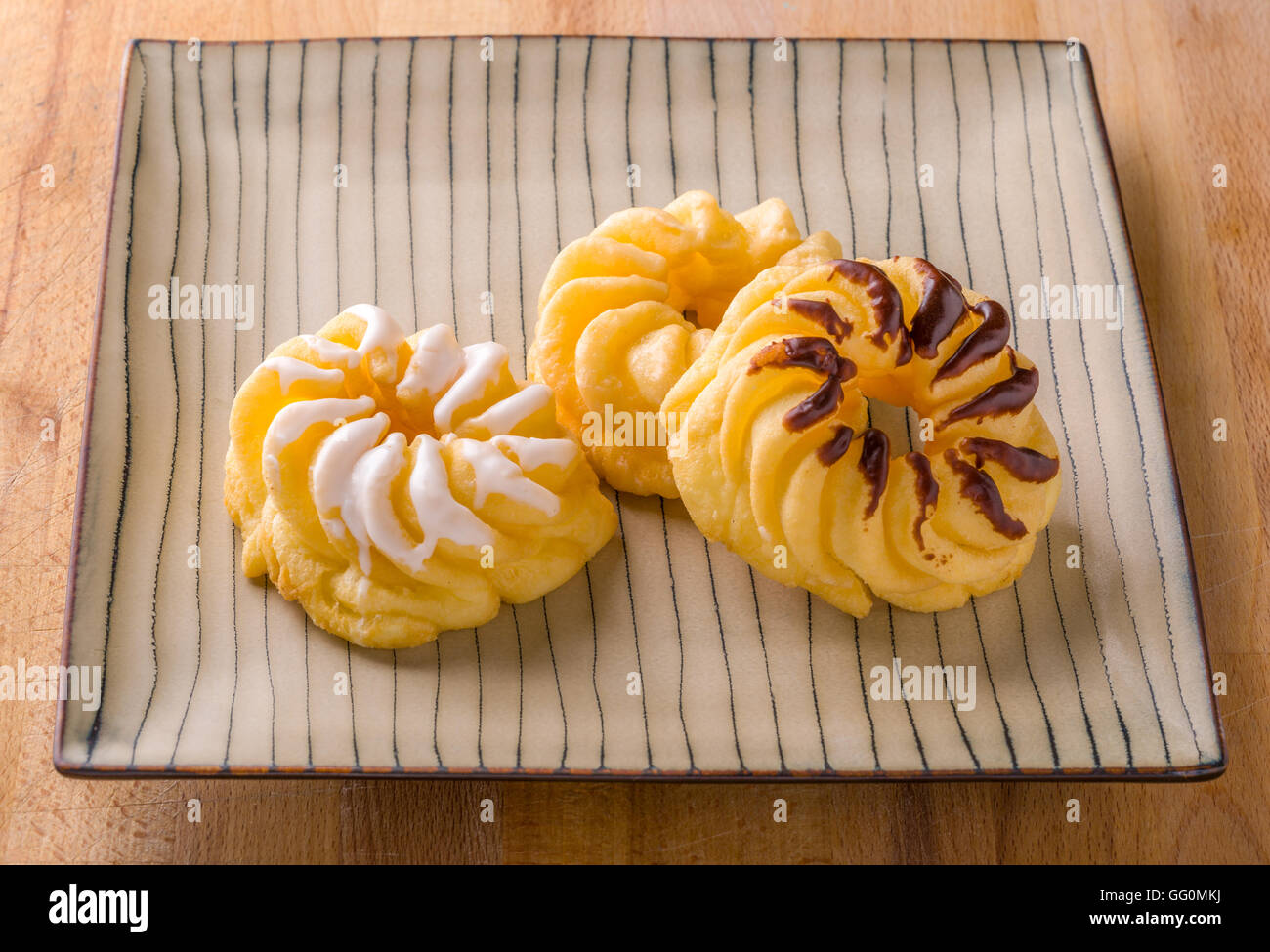 Three traditional French cruller, chocolate, plain, vanilla on a bamboo ...
