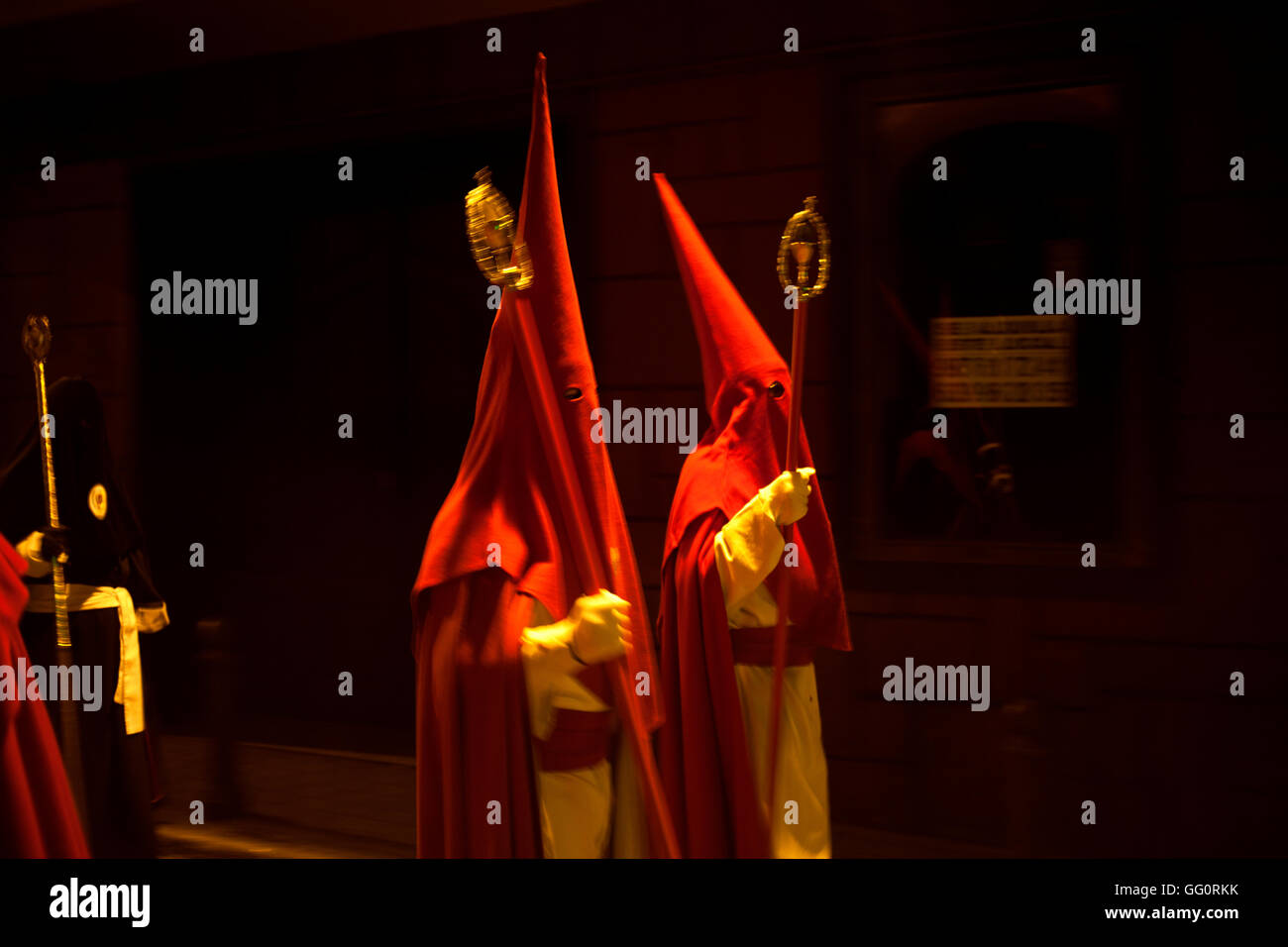 Hooded penitents holding red hats during an Easter Holy Week procession ...