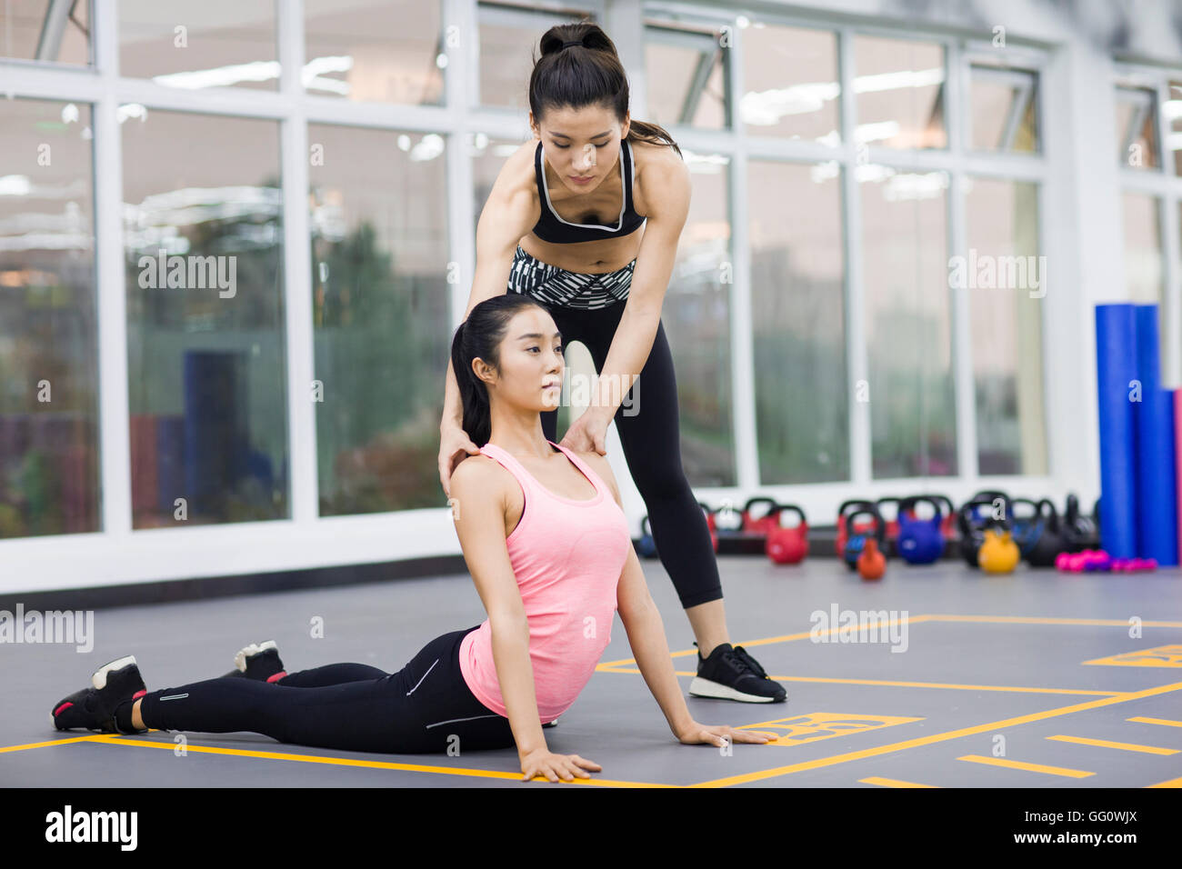 Yoga instructor helping young Chinese woman with pose Stock Photo - Alamy