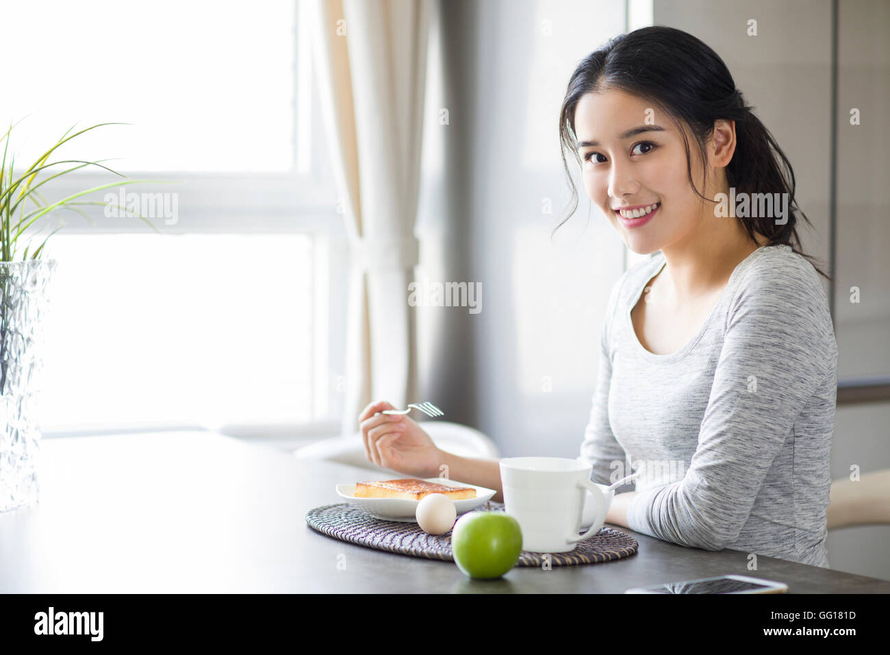 Young Chinese woman eating breakfast at home Stock Photo - Alamy