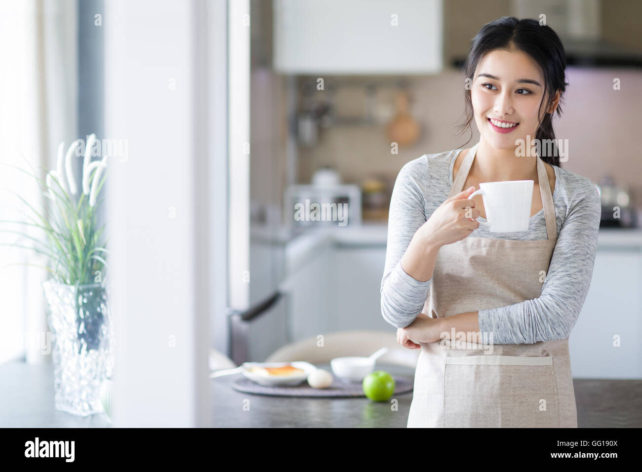 Young Chinese woman drinking coffee at home Stock Photo - Alamy