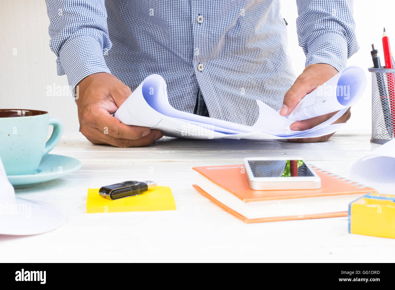 Man architect with house plans in his hand and equipment on white table ...
