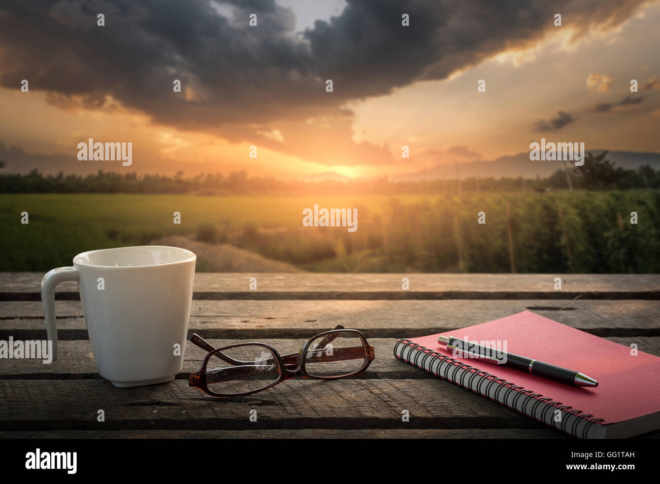 Pen, opened notebook, glasses, and coffee cup on outdoor wood table in ...