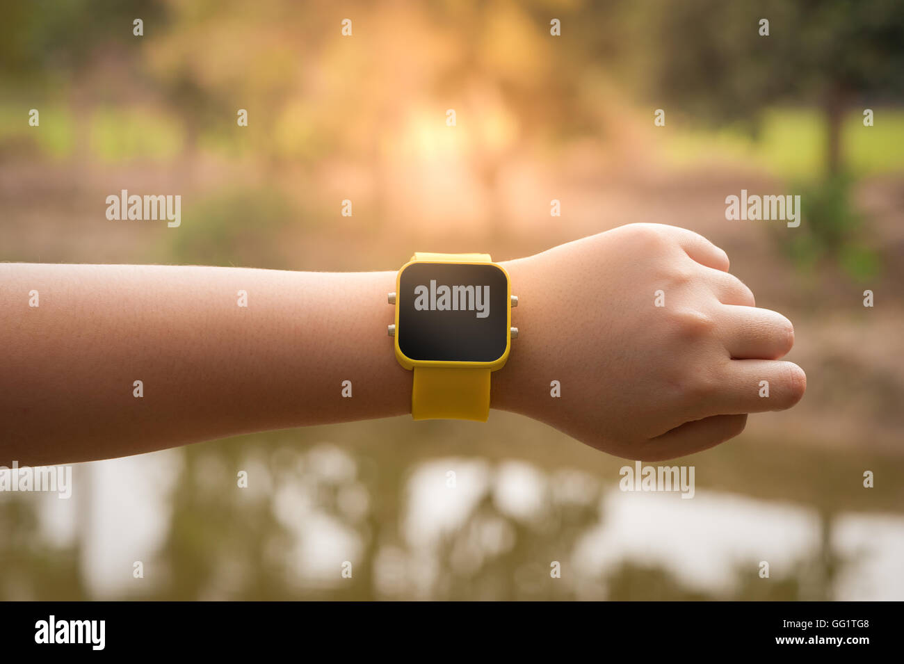 Yellow smartwatch on young woman left arm with nature blurry background ...