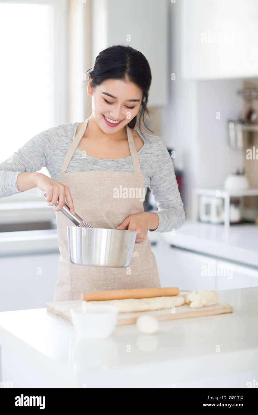 Cheerful young Chinese woman cooking in kitchen Stock Photo - Alamy