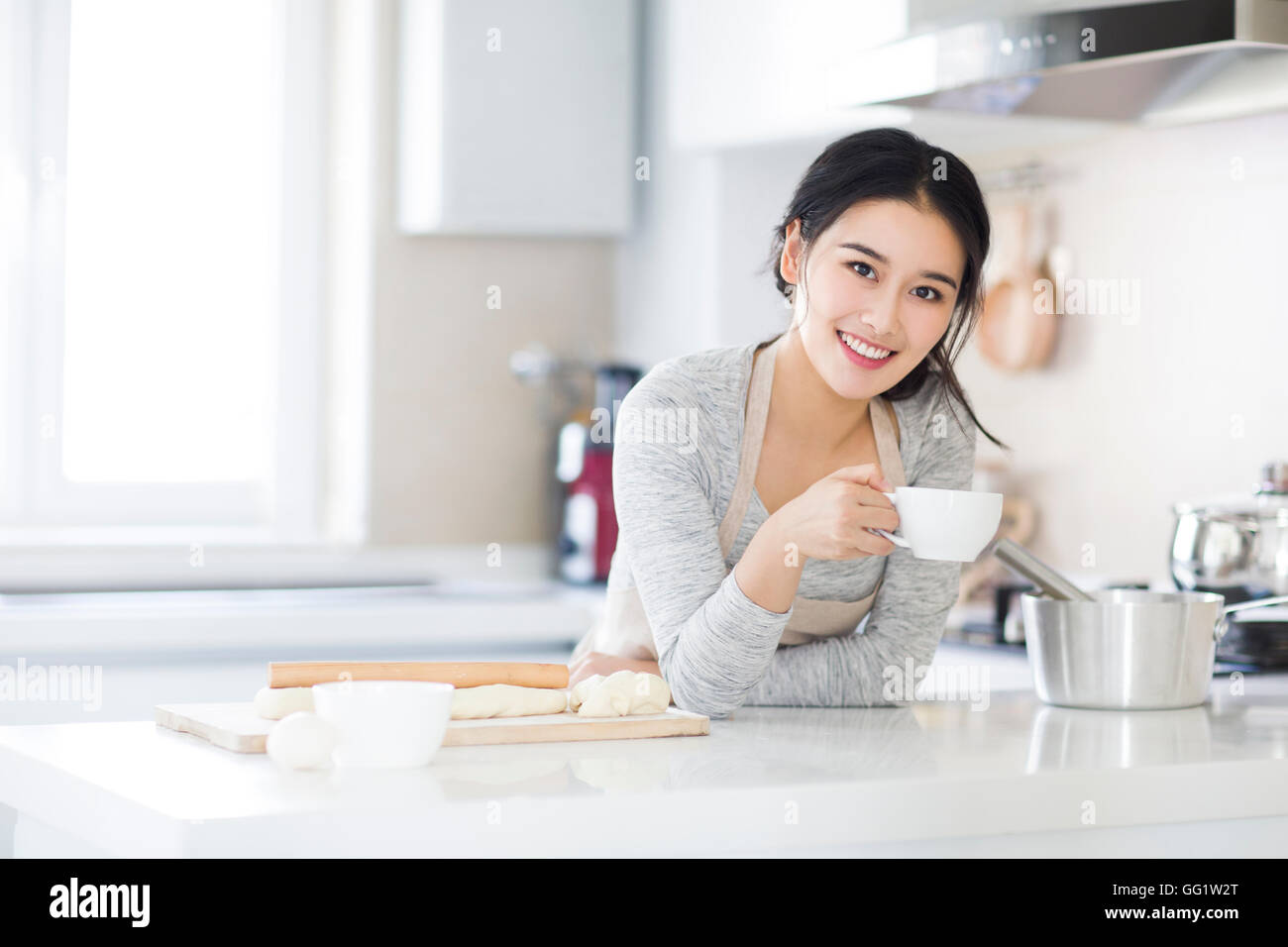 Young Chinese woman drinking coffee in kitchen Stock Photo - Alamy