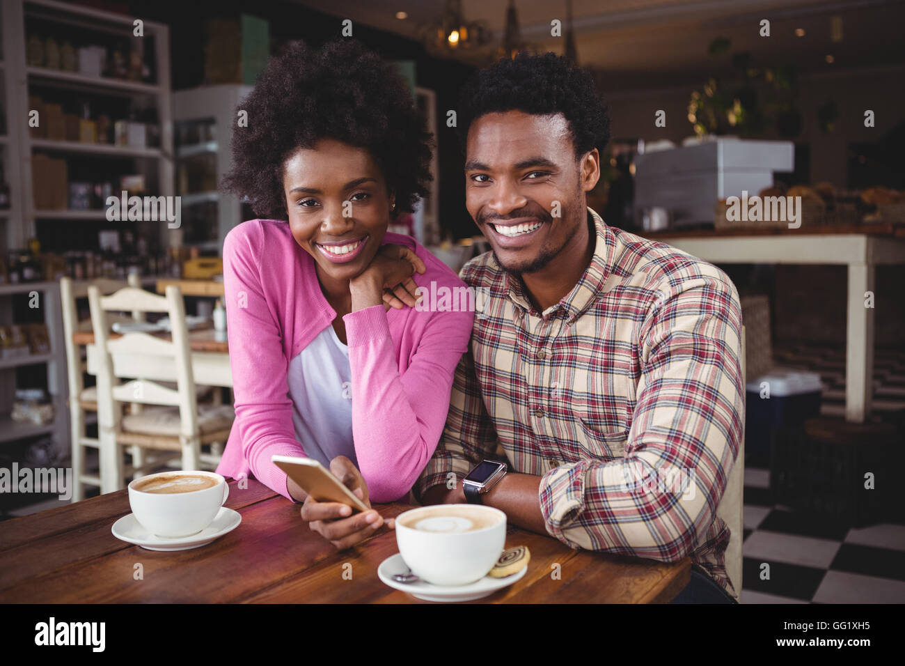 Young couple using mobile phone in cafeteria Stock Photo - Alamy