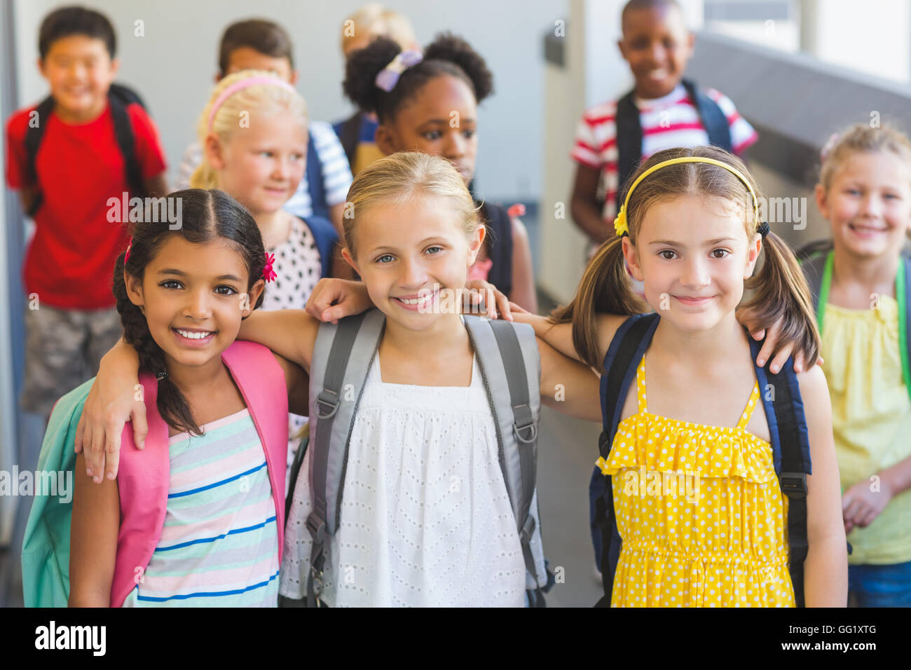 Smiling kids standing with arm around in corridor Stock Photo - Alamy