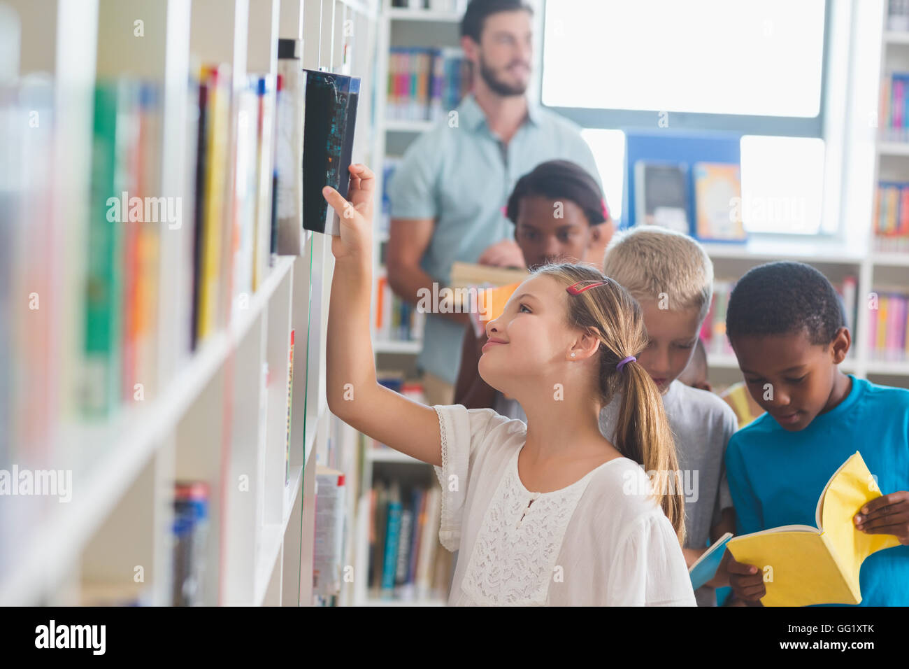 Girl removing book from bookshelf in library Stock Photo - Alamy