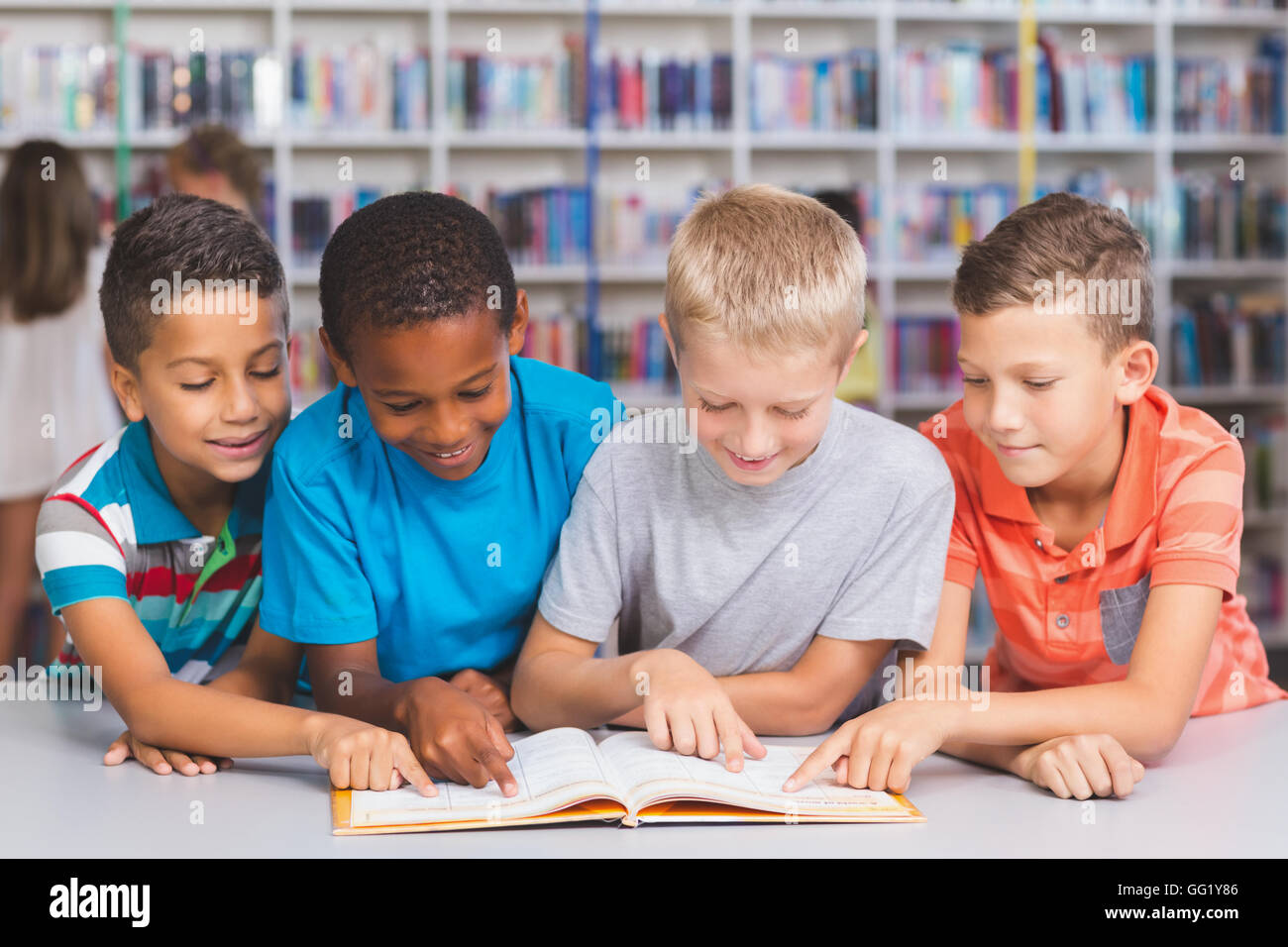 School kids reading book together in library Stock Photo - Alamy